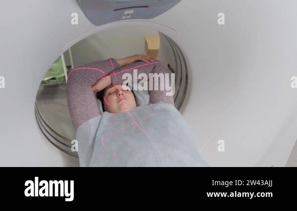 Woman lying on the CT or MRI scanner during machine imaging her body ...