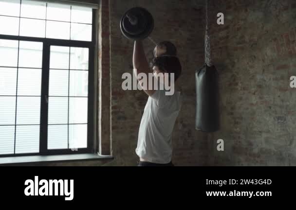 Muscular fitness man lifting barbell above his head in modern gym ...