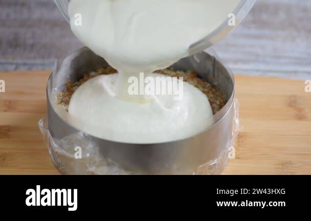 Pouring white mousse into cooking form. Step by step French cake making ...