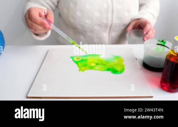 woman applies green paint with an eyedropper, inflates it, abstract ...