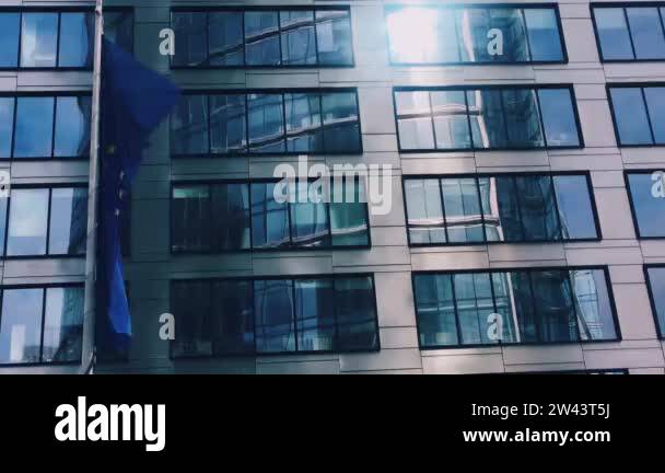European Union flag waving in front of modern corporate office building ...
