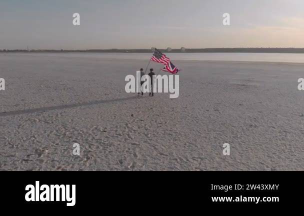 Two men insert flagpoles with the flags of the United States and Great ...