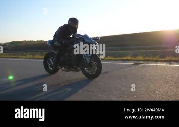 Man riding on modern sport motorbike at highway with sun flare at ...
