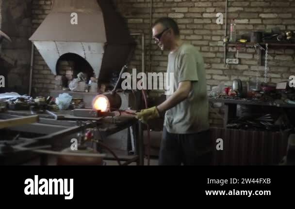 Manipulation with red-hot iron. The blacksmith pulls out an iron bar ...