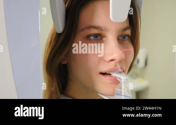 Young smiling female patient undergoing panoramic X-ray investigation ...