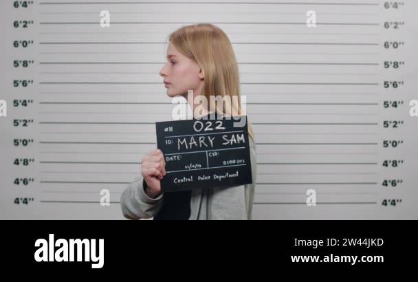 Mugshot of young criminal woman holding sign for photo in police ...