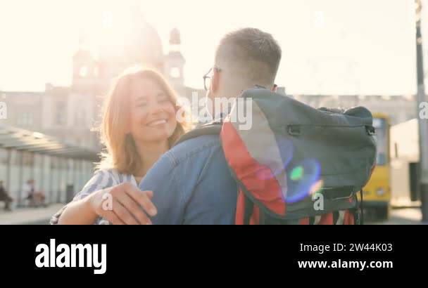 Rear of Caucasian man tourist with backpack meeting beautiful happy ...