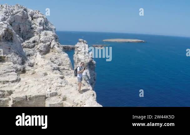 Lockdown shot from the back of a young man taking pictures of the sea ...