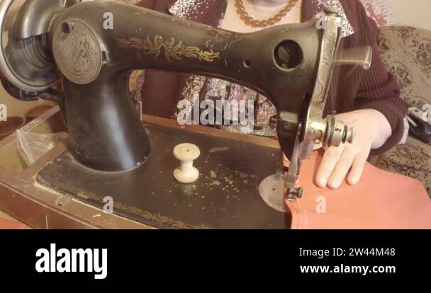 grandmother sews a red flag on an old sewing machine of the Soviet ...