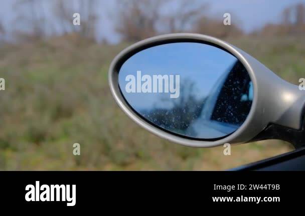 A rear view mirror of a car driving inside the bad route way inside the ...