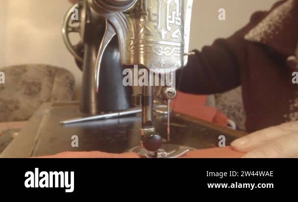 grandmother sews a red flag on an old sewing machine of the Soviet ...