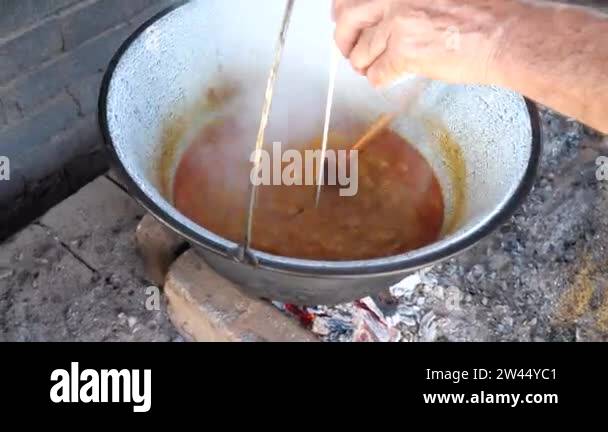 Chef pours salt into prepared pork goulash in deep enamel kettle on ...