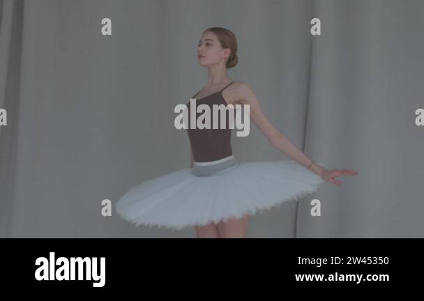 Female dancer ballet on a light coloured background performs smooth ...