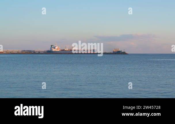 Distant view of a port with docked cargo ships, calm blue sea and sky ...