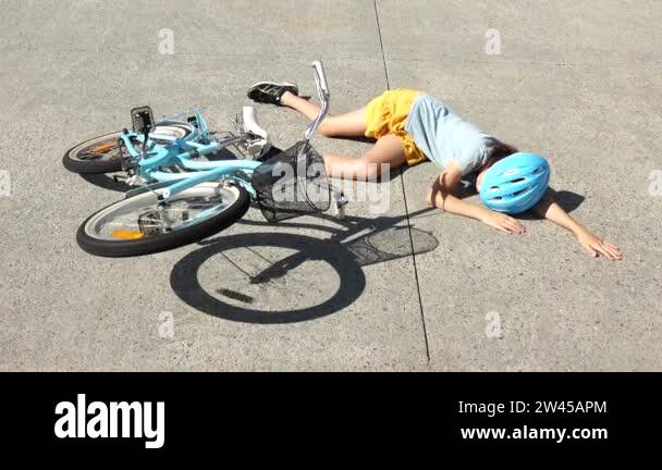 Young girl (female age 10-11) fallen of a bicycle laying down beside ...
