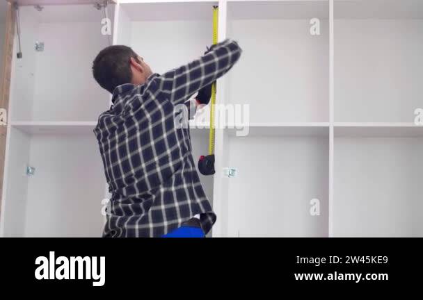 Carpenter measuring shelves in an empty apartment, where he started ...