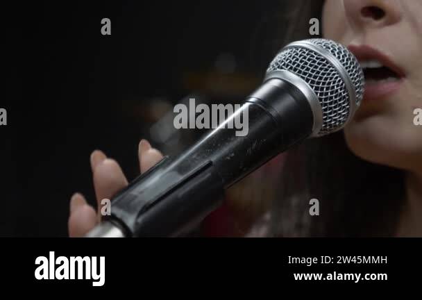 Woman singer is emotionally singing song into microphone, close up ...