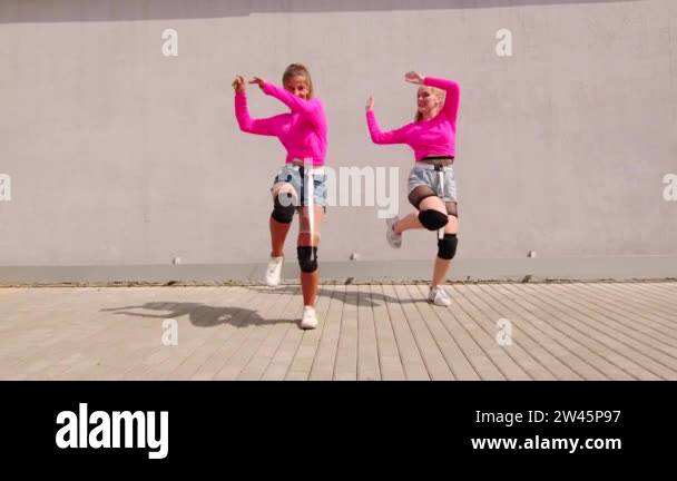 Two cheerful young girls in short shorts dancing hip hop, performs ...