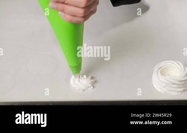 Pastry chef makes Anna Pavlova mini cakes, pour the filling using a ...