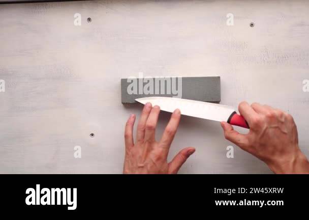 White Man's Hand Sharpening a Kitchen Knife on a Rectangular Stone ...