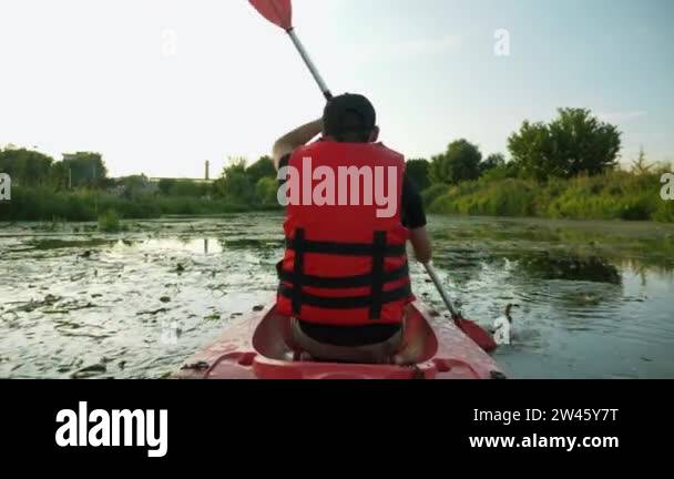 Sportive strong man in life vest is rowing in kayak on river. Male ...