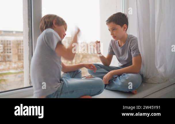 Friends play to Rock Paper Scissors game on window sill. Brothers play ...