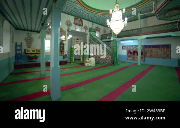 Muslim mosque teacher is reading quran in small historic wooden masjid ...