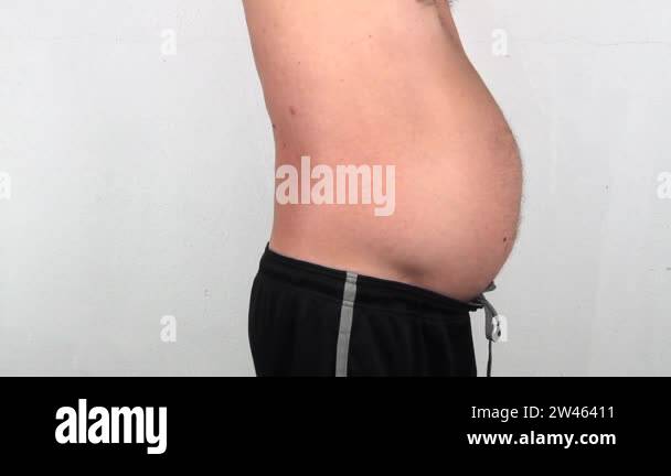 profile view of a pot bellied man who is gently cuddled on his belly by ...