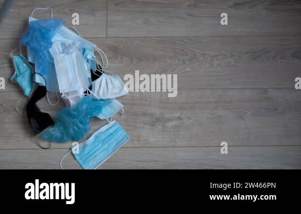 Covid-19 disposable ppe waste. A man sweeps up medical waste, used face ...