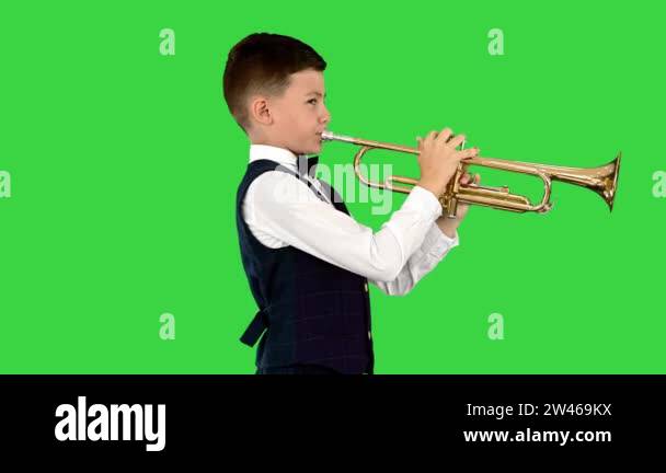 Young boy in a bow tie playing the trumpet swaying from side to side on ...