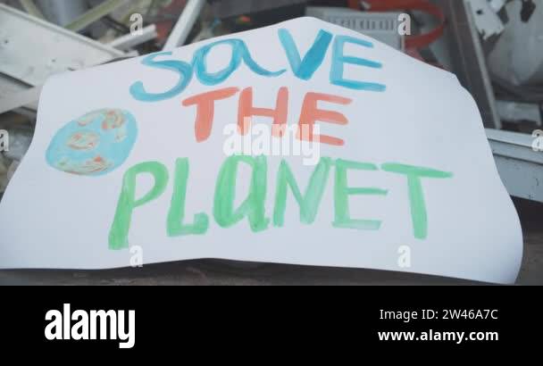 Close-up of Save the planet placard lying on trash. Concept of eco ...