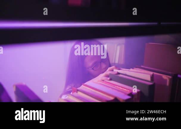 A girl is sorting through books on the shelves of the library, magic ...