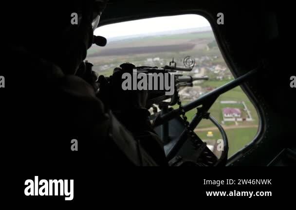 Soldier holding machine gun and looking in a hatch of a flying copter ...