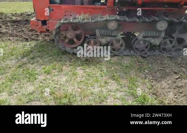 A farmer cultivates a field on a crawler tractor and loosens the soil ...