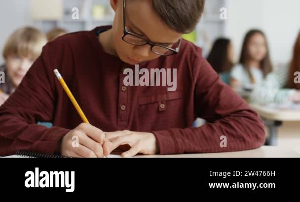 Close up of the Caucasian teen small nice boy in glasses writing a ...