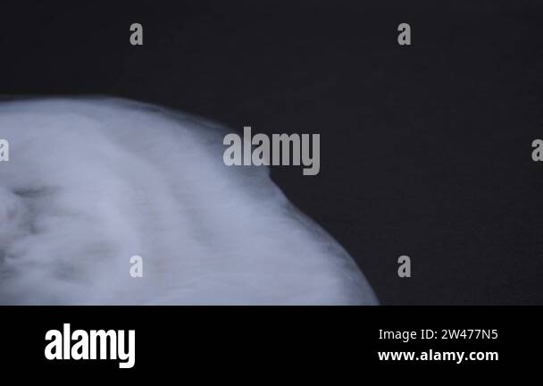 Clouds of thick smoke roll over the black background and creep low to ...