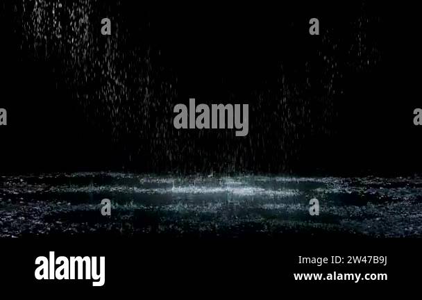 Spray spatters rain fall against on the water surface which glow. Black ...