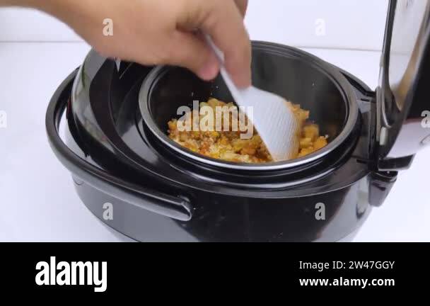 Macro Video of a multicooker. The man opens the pan and mixes the dish ...