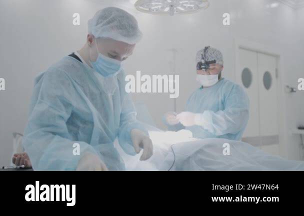 Two surgeons prepare patient for surgery. Action. Two young surgeons ...