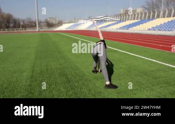 Fit active good looking young woman does leg stretching exercise to ...