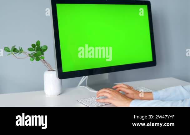 Woman typing on a computer keyboard, monitor with a green screen ...