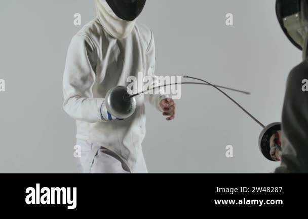 Duel of two fencers on a white background in the studio. Two professional fencers show masterful ...