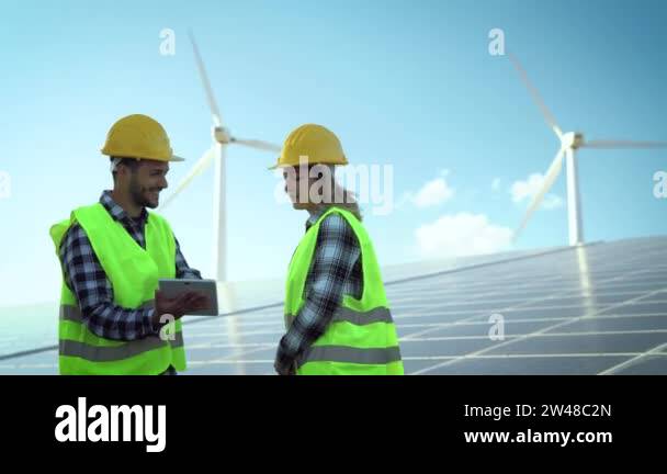People working for alternative energy with wind turbine and solar panel ...