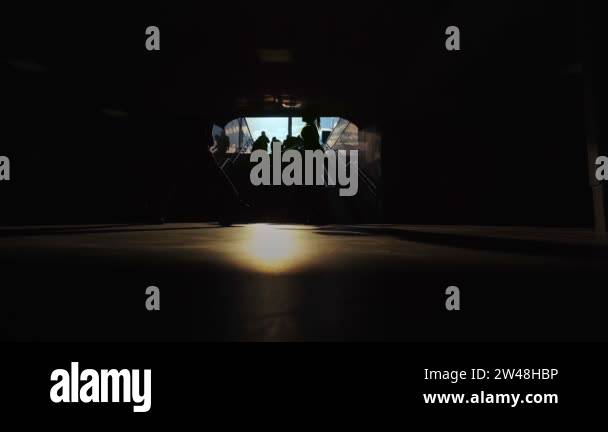 People walk through dark underpass near stairs at susnet, underground ...
