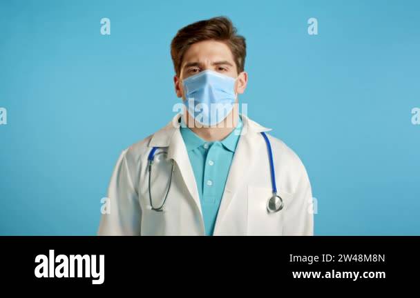 Young doctor man in professional medical white coat and mask covers his ...