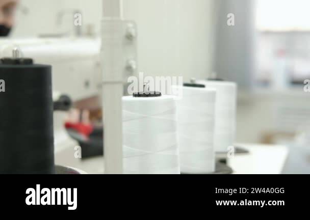 Close-up of a spool with a fine thread on a sewing machine in a ...