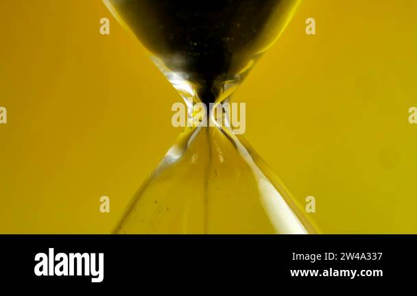Extreme close-up of black sand running down through hourglass on a ...