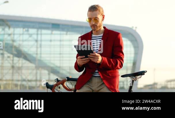 Caucasian young handsome man standing at bicycle and using tablet ...