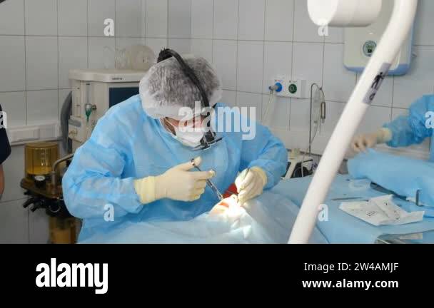 Dental surgeon giving anesthesia injection while performing surgical ...