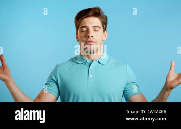 Calm man in blue relaxing, meditating. He calms down, breathes deeply ...